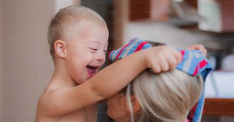 웃는 장애인 다운 증후군 아이가 알아볼 수 없는 어머니와 함께 실내에서 즐거운 시간을 보내고 있습니다 사진 Unsplash의 머리 이미지