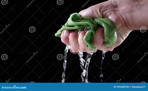 Hand Squeezes A Wet Green Rag With Falling Drops Of Water On A Black Background Stock Footage