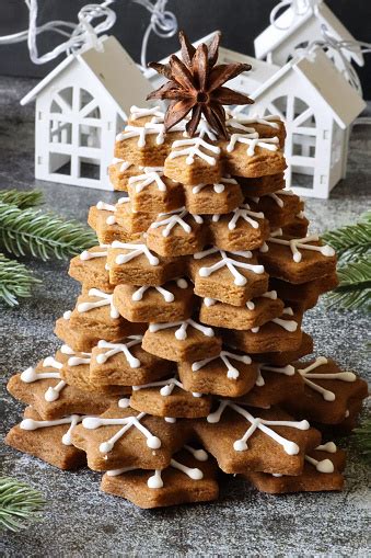 누적 진저 브레드 눈송이 비스킷에 흰색 왕실 장식 샬레 요정 조명과 회색 표면에 가문비 나무 바늘 배경으로 장식 스타 아니스 로 얹어 형성 크리스마스 트리의 클로즈업 이미지