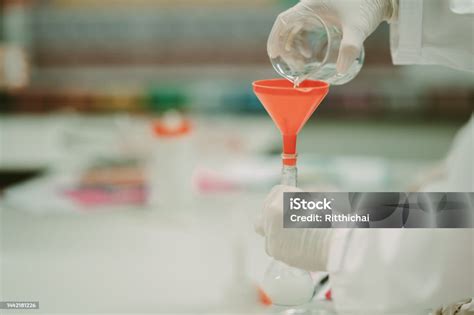 실험실 연구 개념 학생을 위한 교실의 테스트 화학 실험실 흐릿한 배경의 비커에서 체적 플라스크에 화학 용액 물질을 붓는 손을 닫고 안전 장갑 손 Stem 주제에 대한 스톡