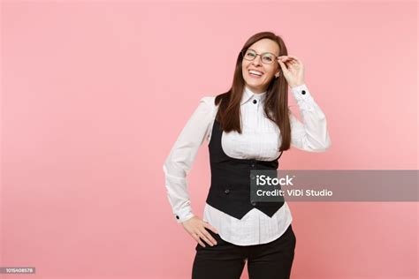 검은 양복에 흰색 셔츠를 들고 안경 파스텔 핑크 배경에 고립 된 젊은 웃는 아름 다운 비즈니스 여자 여자 보스입니다 성과 경력 부 개념입니다 광고에 대 한 공간을 복사