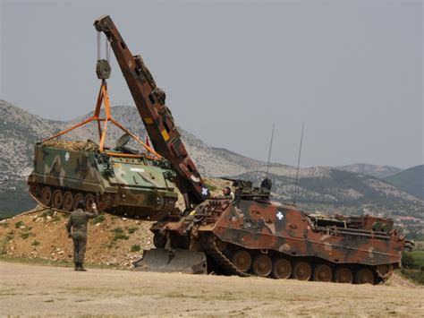 Army Tank Being Lifted by Crane on Dirt Field