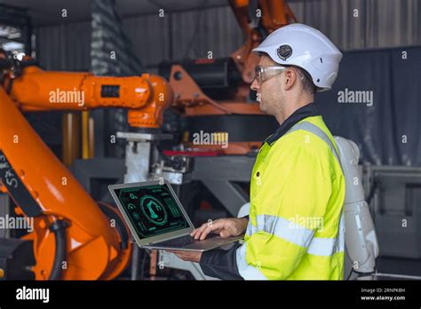 engineer male using laptop computer control operate industry robot arm