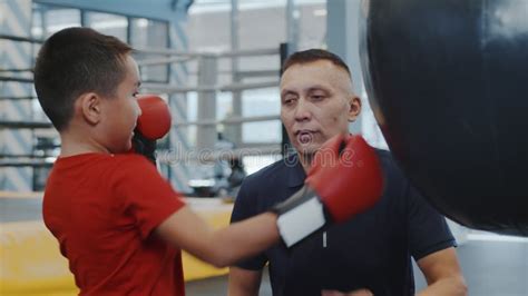 Young Asian Boy In Boxing Gloves Working Out With A Punching Bag And