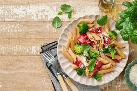 브로콜리와 빨간 구운 피망을 곁들인 통곡물 파스타 펜네와 밝은 나무로 된 소박한 배경 테이블 비건 파스타 전통 이탈리아 요리 플랫 레이 공간을 복사합니다 0명에 대한 스톡