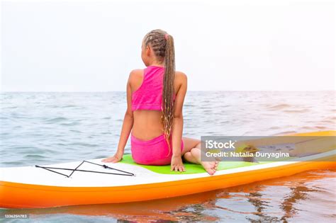 여름 일몰의 색상으로 바다에 패들 보드에 앉아 어린 소녀 땋은 머리에 대한 스톡 사진 및 기타 이미지 땋은 머리 10 11