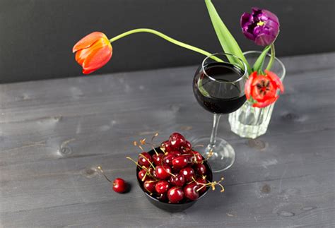 레드 와인 잔 검은 나무 배경에 잘 익은 체리와 신선한 튤립 꽃 유리 그릇 0명에 대한 스톡 사진 및 기타 이미지 0명