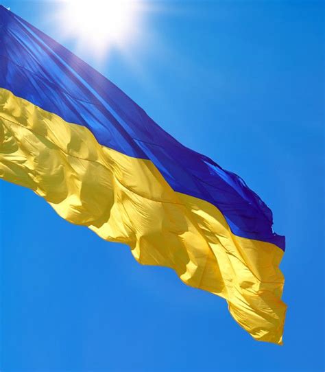 Текстильный флаг украины развивается на фоне ясного голубого неба ...