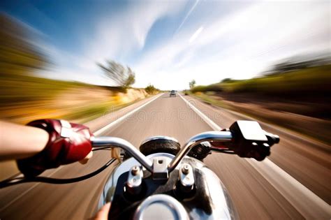 A Person Riding A Motorcycle On A Road With Blurry Trees In The Background And A Car Driving
