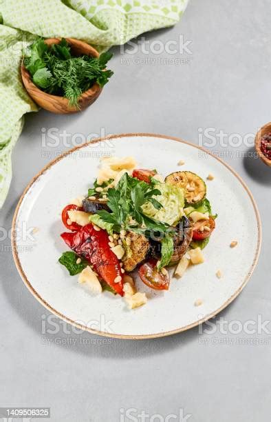 콘크리트 배경에 구운 야채 채소 및 치즈를 곁들인 샐러드 그릴에 파프리카 호박 가지 및 토마토와 함께 따뜻한 샐러드 채소 샐러드와 미적 구성 여름 메뉴 개념