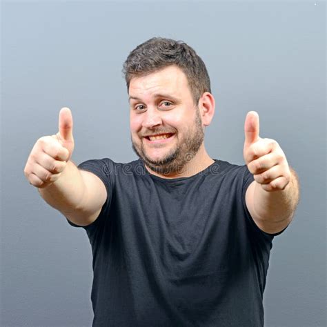 Retrato De Un Joven Gordito Que Muestra El Pulgar Hacia Abajo Con Fondo Gris Foto De Archivo