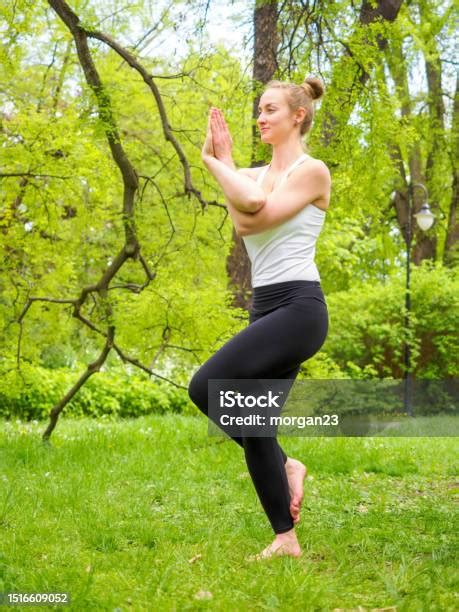 화창한 여름날 공원에서 야외 요가를 연습하는 젊은 예쁜 금발 여자 가루다아사나 포즈에 서 있다 건강한 생활방식에 대한 스톡 사진