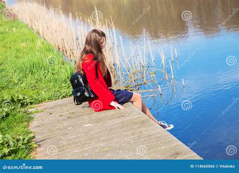 Сиротливый молодой девочка подросток сидя на речном береге Стоковое Фото изображение