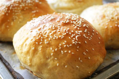 갓 구운 수제 흰 빵 버거 빵 햄버거 배 기름 증거 종이 양피지 줄 지어 트레이에 참깨를 뿌린 빵 롤의 클로즈업 이미지 전경에 초점을 맞추고 0명에 대한 스톡 사진 및 기타