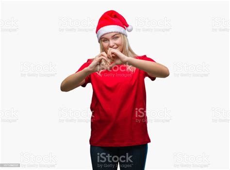 젊은 백인 여자 마음 기호와 손으로 모양을 보여주는 사랑에 웃 고 고립 된 배경 위에 크리스마스 모자를 쓰고 낭만적인 개념입니다