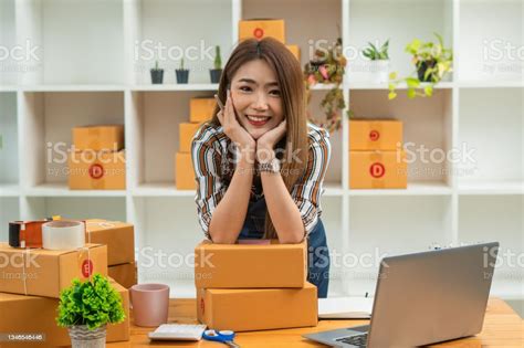 젊은 아시아 여성의 중소기업 기업가 집에서 온라인 쇼핑을위한 노트북과 함께 작업 가정에서 포장을위한 상자와 함께 쾌활하고 행복 비즈니스 온라인을 위한 자신의 비즈니스