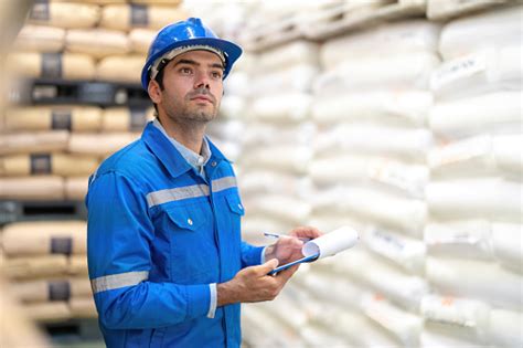 백인 유럽 남성 엔지니어의 반신 샷 플라스틱 산업에 서 창고에 있는 제품 살펴보기 헬멧과 유니폼을 착용하십시오 펜과 메모 목록