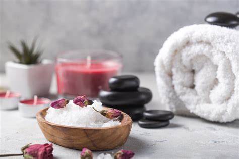 분홍색 장미 바다 소금 아로마 오일이 있는 스파 아로마 에센셜 과 천연 향기 소금의 마사지 오일 병의 아름다움 여전히 생활 돌 콘크리트 회색 테이블에 촛불 스파 트리트먼트의