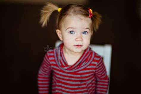 Очень милая маленькая девочка в Striped платье сидя на стуле Стоковое Фото изображение