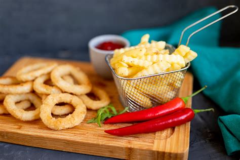 패스트 푸드 빵가루 입힌 양파 반지는 나무 판에 소스와 함께 감자 튀김으로 튀긴 것입니다 0명에 대한 스톡 사진 및 기타 이미지