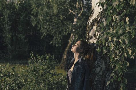 Caucasian Woman Leaning On Tree Trunk Stock Photo