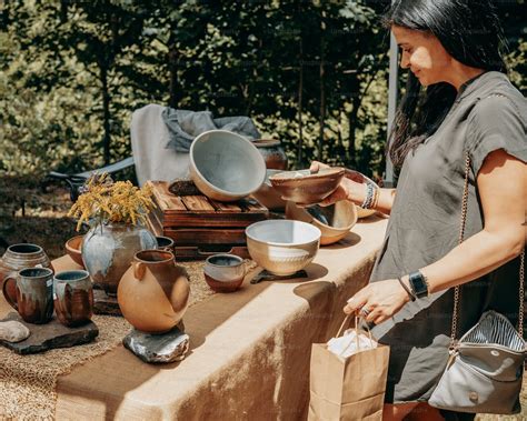 냄비와 프라이팬으로 가득 찬 테이블 옆에 서 있는 여자 사진 Unsplash의 도자기 이미지