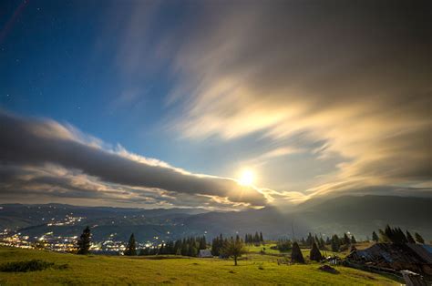 여름 밤 산 파노라마입니다 푸른 잔디 산 청소 파란 저녁 하늘 복사 공간 배경에 스프루 스 나무 계곡 아래 이동 자동차와 주거 조명을 가진 밝은도로 0명에 대한 스톡 사진