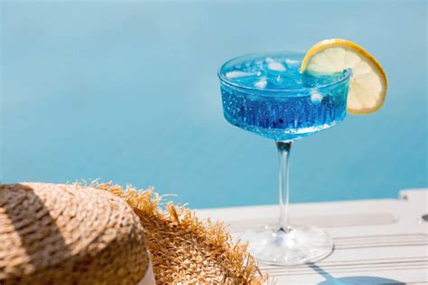 수영장 배경에 맛있는 파란색 칵테일 블루 라군과 노란색 레몬 한 잔 알콜 칵테일 육즙이 많은 과일 블루와 Curacao 리큐어 아이스 큐브 및 레몬 조각 0명에 대한 스톡