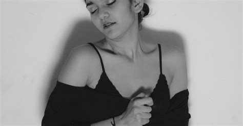 Dl 가슴에 손 갈색 머리 검정 드레스 고립 된 배경 고요한 표정 눈을 감다 델리 드레스 명상 적 미니멀리스트 미묘한 그림자 부드러운 조명 블랙 앤