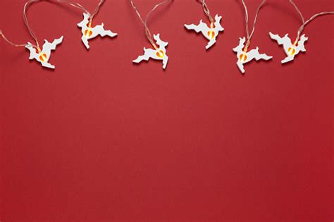 어두운 붉은 배경에 흰색 실행 사슴의 형태로 따뜻한 빛과 크리스마스 나무 화환 엽서 레이아웃에 대해 비어 있습니다 축제 새해