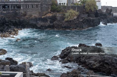 화산 바위 절벽에 있는 집들의 전망 절벽의 화산암에 부딪히는 파도 거친 바다 검은 바위 푸에르토 데 라 크루즈 테네리페 카나리아 제도 스페인 0명에 대한 스톡 사진 및 기타