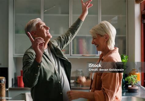 은퇴 유대감이나 재미를 위해 집의 부엌에서 노인 부부와 함께 춤추고 사랑하고 미소 짓습니다 재미 있거나 행복하거나 웃는 노인 남성과 여성이 아파트에서 음악을 듣거나 스트리밍