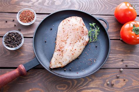 닭 가슴살에서 원시 스테이크는 허브와 향신료와 함께 뿌 렸 다 고 요리 준비가 검은 철 프라이팬에 빨간 토마토와 후추 상단 보기 옆 나뭇가지 분기와 가금류에 대한 스톡 사진