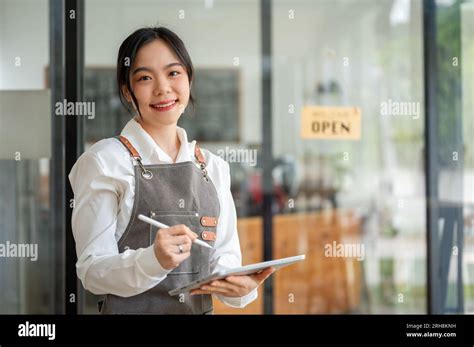 A Friendly And Pretty Asian Female Cafe Worker Or Waitress In An Apron
