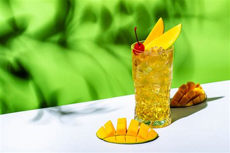 망고 럼 콜린스 화이트 럼 시럽 생강 맥주 레몬 주스 얼음 및 망고와 알코올 칵테일 음료 녹색 배경 복사 공간 망고에 대한 스톡