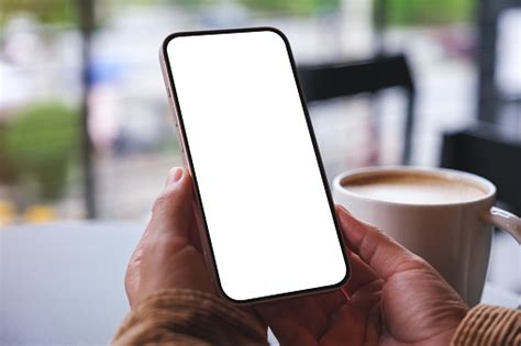 테이블 위에 커피 잔이있는 빈 데스크톱 화면이있는 휴대 전화를 들고있는 여성의 모형 이미지 35 39세에 대한 스톡 사진 및 기타 이미지 35 39세 공란 디지털