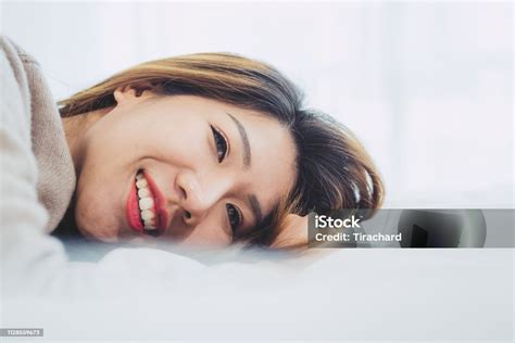 초상 집에서 아침에 침대에서 아름 다운 젊은 아시아 여자 쾌활 한 아시아 여자 편안한 스웨터를 착용 하 고 그녀의 침대에 웃 고 편안한 방입니다 라이프 스타일 홈 개념에서