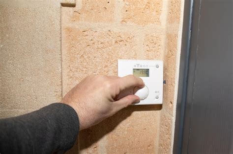 Premium Photo Man Hand Man Changes The Temperature On Smart Heating Thermostat In Interior House