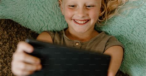 태블릿을 들고 바닥에 누워 있는 어린 소녀 사진 Unsplash의 노는 이미지