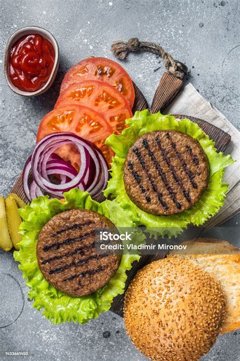 나무 서빙 보드에 비건 구운 패티 토마토 양파를 곁들인 고기 없는 버거를 재배합니다 회색 배경 위쪽 보기 햄버거 류에 대한 스톡 사진 및 기타 이미지 Istock