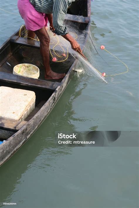 인도 어 부 작은 나무 낚시 보트 바다 잡기 작은 물고기 씨 캐치에 의해 손으로 흰색 나일론 낚시 그물에 당기는 위에 기대어 앉아 전통 핑크 룬 기 사 롱 둘리에 물고기