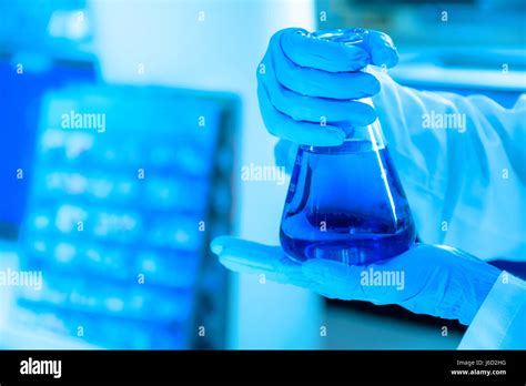 Scientist With Sample Flask In Hand Researching In Laboratory Stock