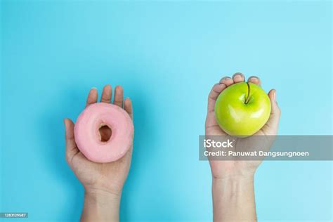 녹색 사과와 분홍색 도넛을 들고 있는 여성 과일 중에서 선택하는 여성은 건강한 음식이며 달콤한 것은 건강에 해로운 정크 푸드입니다 다이어트 비만 생활 습관 및 영양 개념