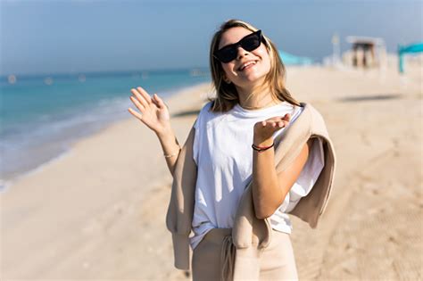 해변에서 걷는 캐주얼 한 옷을 입고 선글라스를 착용한 매력적인 여성의 전체 길이 초상화 20 24세에 대한 스톡 사진 및 기타 이미지 20 24세 낮 물 Istock