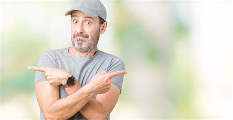 잘생긴 중 년 노인의 수석 남자 이상 스포츠 모자를 쓰고 절연 배경 손가락으로 양쪽 모두를 가리키는 다른 방향 반대 가리키기에 대한 스톡 사진 및 기타 이미지 Istock