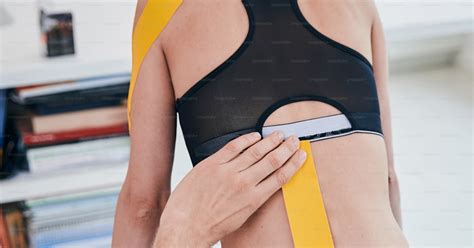 의료 사무실에서 키네시오 테이프를 적용하는 의사 Osteopath가 있는 동안 마사지 테이블에 앉아 인식할 수 없는 여성 환자의 자른 머리 뒷면 보기 초상화 사진