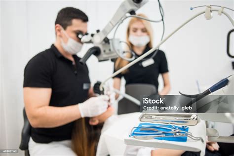 남자 치과 의사 및 치과 사무실에서 현미경으로 환자의 치아를 치료 하는 여성 도우미 치과 기구에 초점 약 치과 및 건강 관리 개념입니다 치과 장비 건강 진단에 대한 스톡