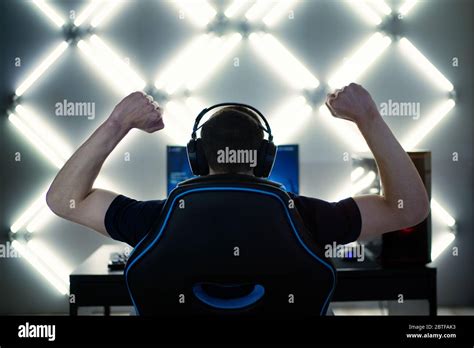 Back View Of Young Gamer Guy In Headphones Screaming And Rejoicing