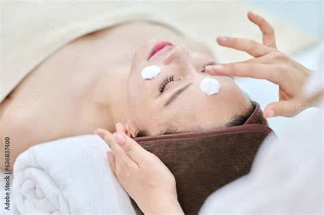 아시아 한국의 젊은 여자 모델이 스파 또는 피부관리전문점 또는 피부과 병원에서 갈색 두건을 쓰고 침대에 누워 베이지색 대형