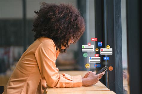 미소 짓는 아프리카계 미국인 사업가가 현대적인 작업 공간에서 스마트폰으로 소셜 미디어에 참여하고 있습니다 소셜 네트워킹에 대한 스톡 사진 및 기타 이미지 Istock